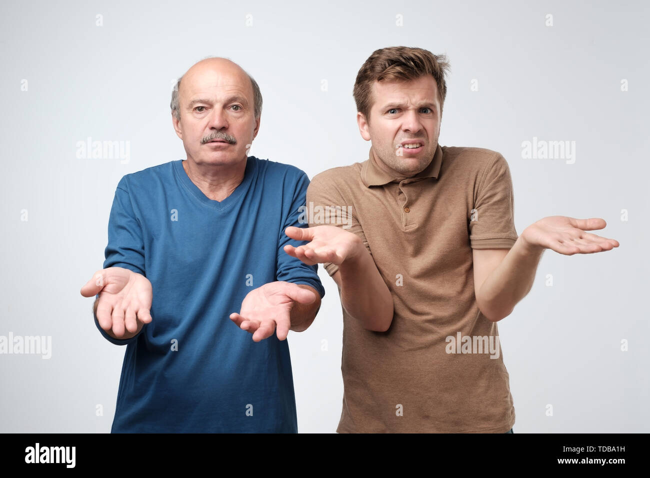 father and son raise hands as shows being confused Stock Photo - Alamy