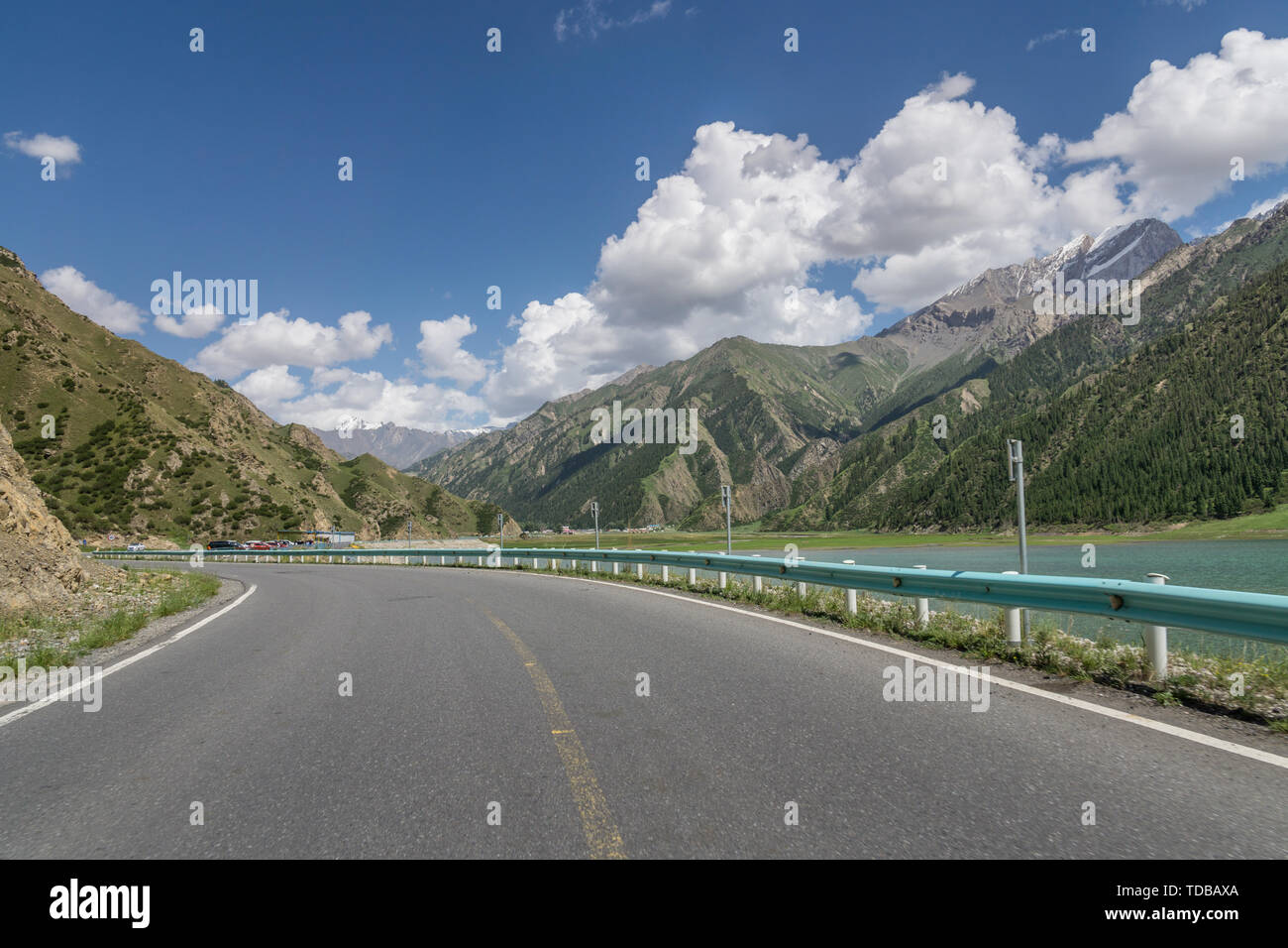 G217 Duku Highway bend in alpine forest under summer blue sky and white ...