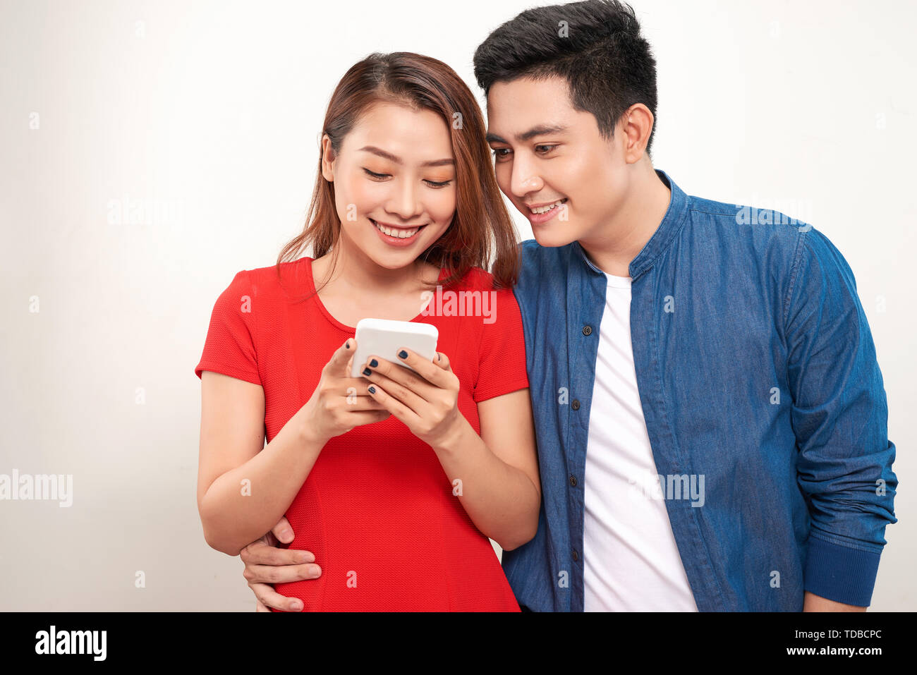 Asian couple using cell smart phone message smile standing on white ...