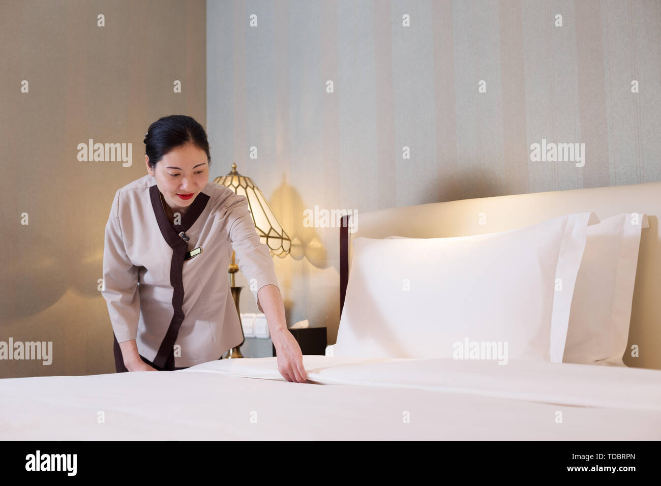 young chinese woman housekeeper makes bed in modern hotel Stock Photo ...