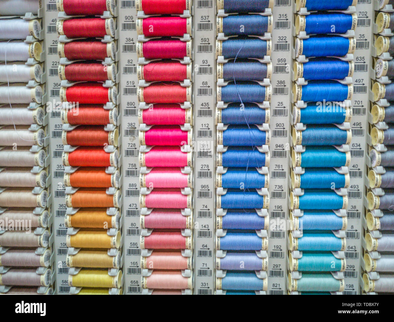Colorful sewing threads on display in shop from dark to light Stock ...