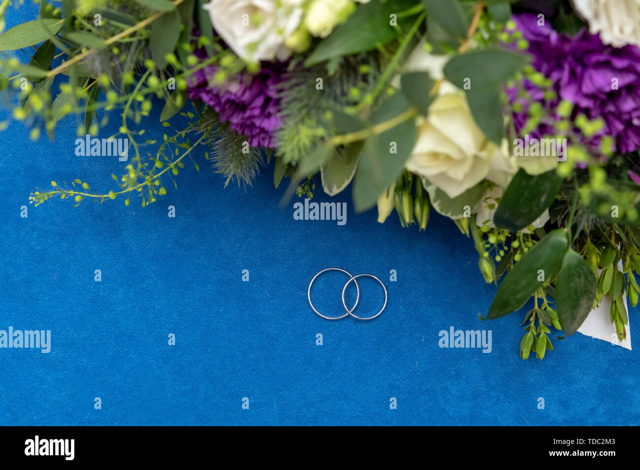 Wedding gold rings on blue background with bouquet of flowers. Symbol ...