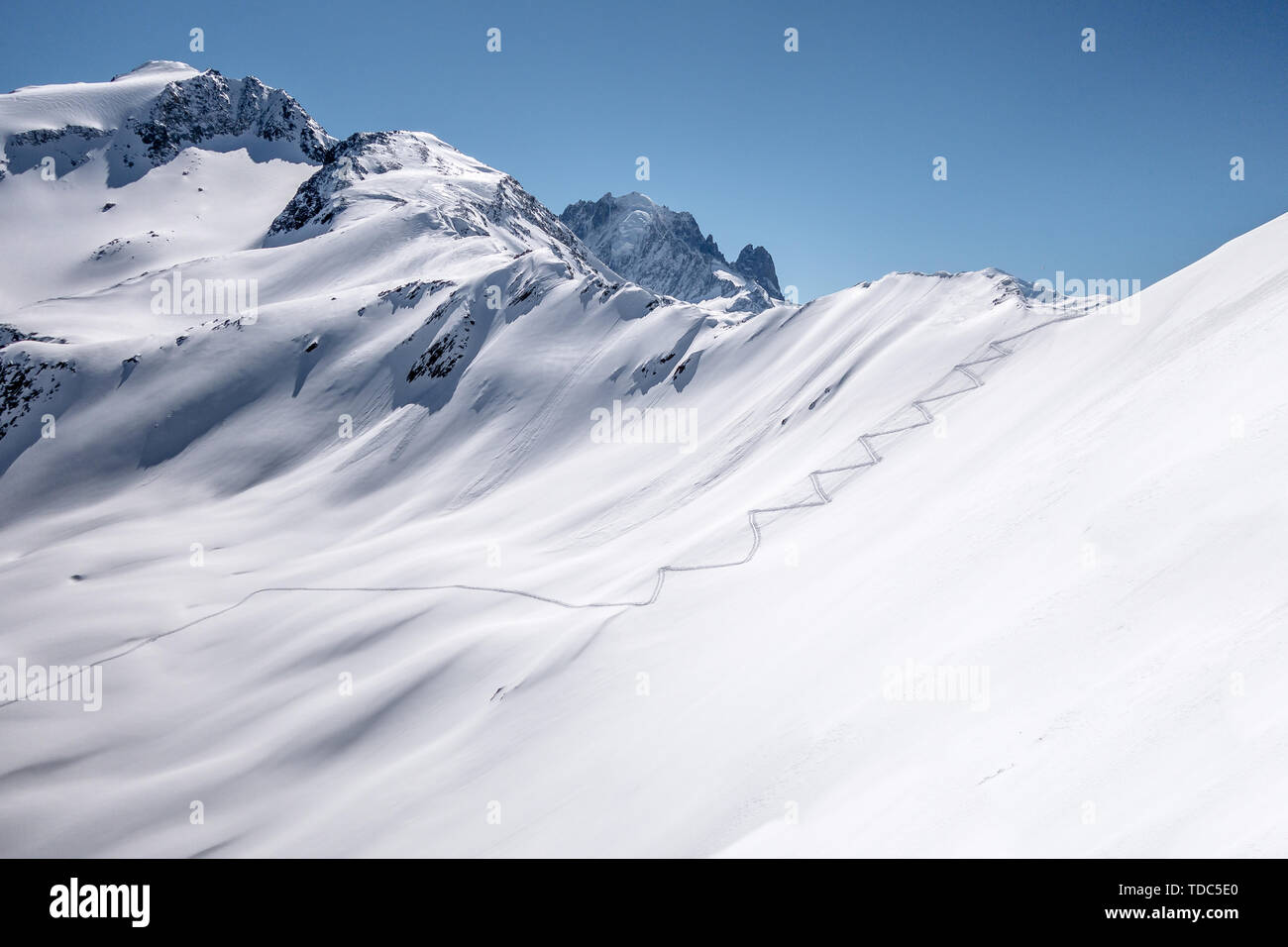 Ski touring track leading up alpine mountain slope to ridge and pass in ...