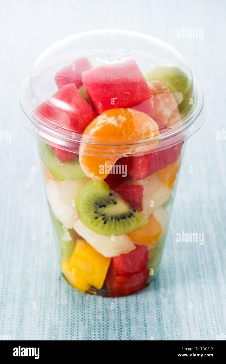 Fresh cut fruit in a plastic cup on blue background Stock Photo - Alamy