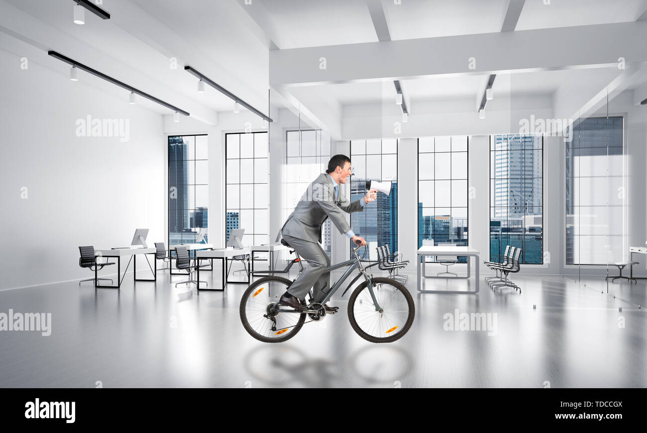 Manager in business suit riding bicycle at conference hall. Businessman ...
