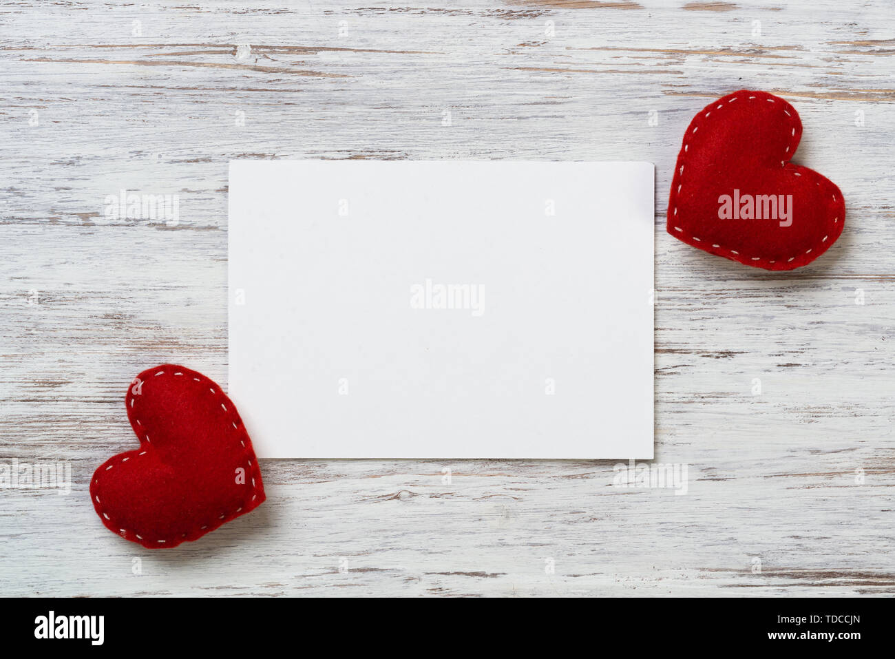 Blank sheet of paper and red love hearts on wooden table. View from ...