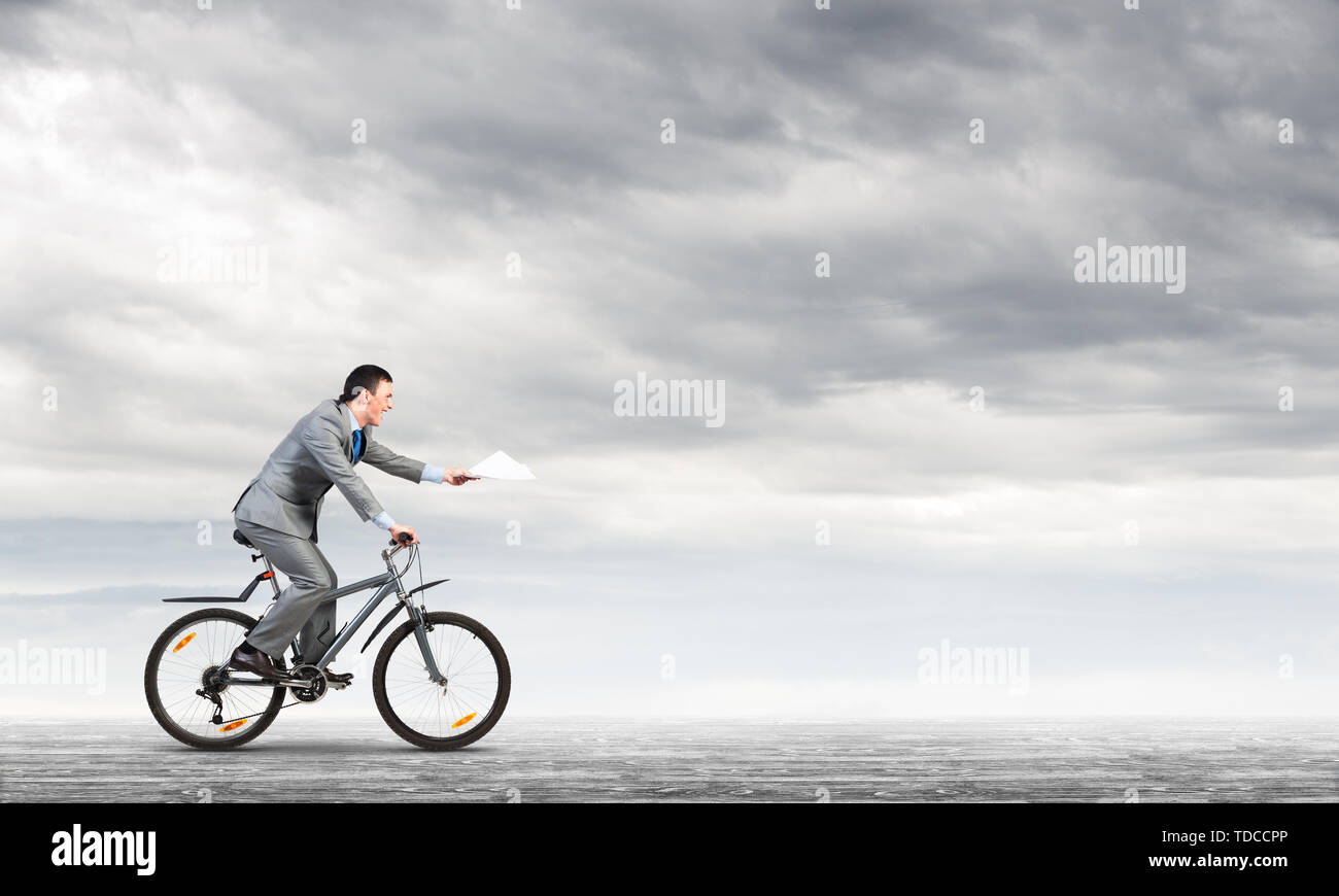 Businessman with paper documents in hand on bike. Deadline for paperwork. Corporate employee in ...