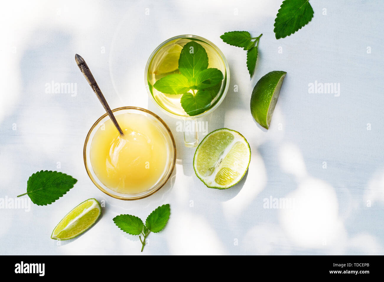 Top view lime tea with mint in a glass cup and honey on a white ...