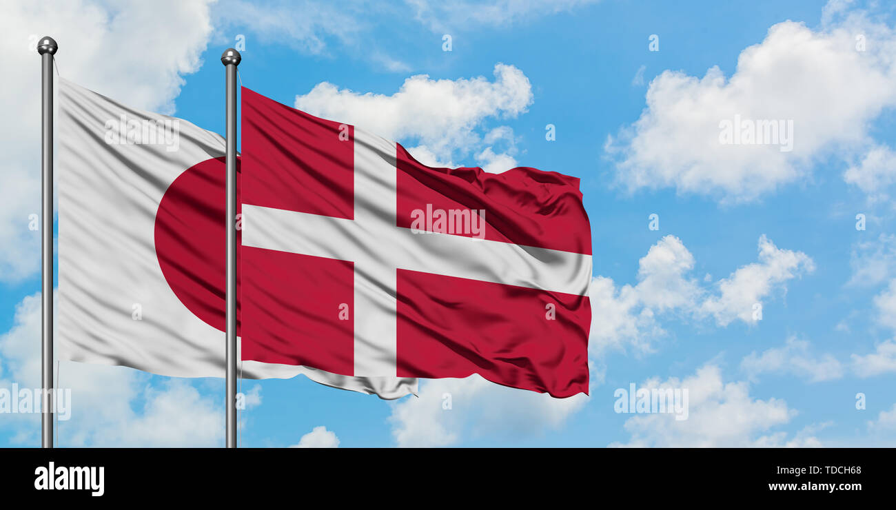 Japan and Denmark flag waving in the wind against white cloudy blue sky ...