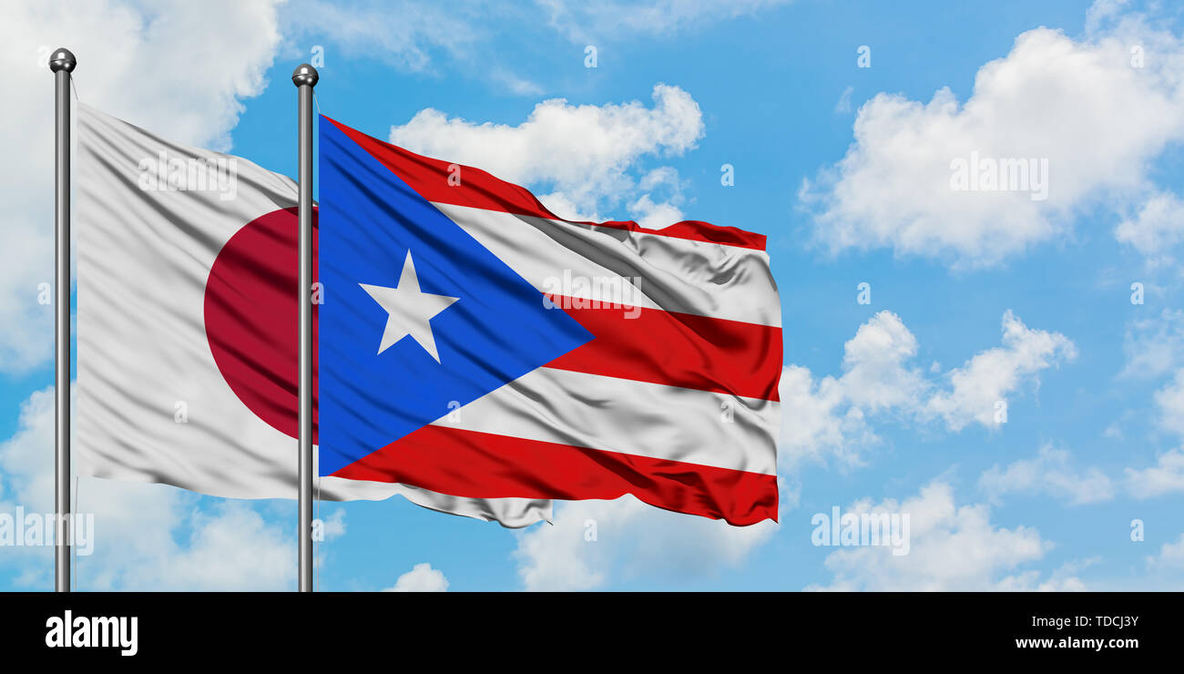 Japan and Puerto Rico flag waving in the wind against white cloudy blue ...