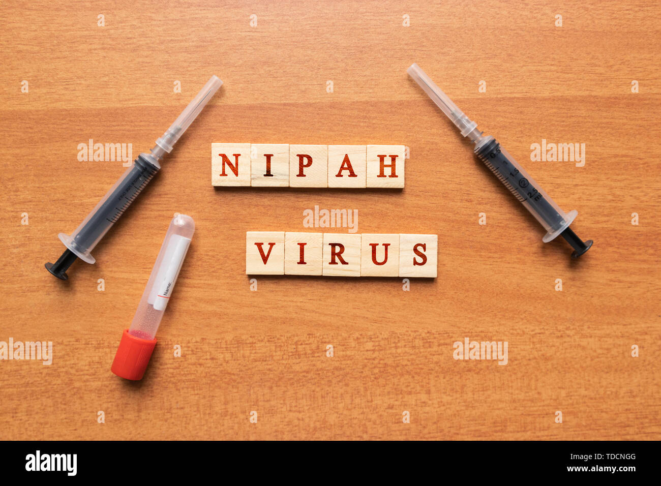 Nipah Virus on a wooden textured background with syringe and vacutainer ...