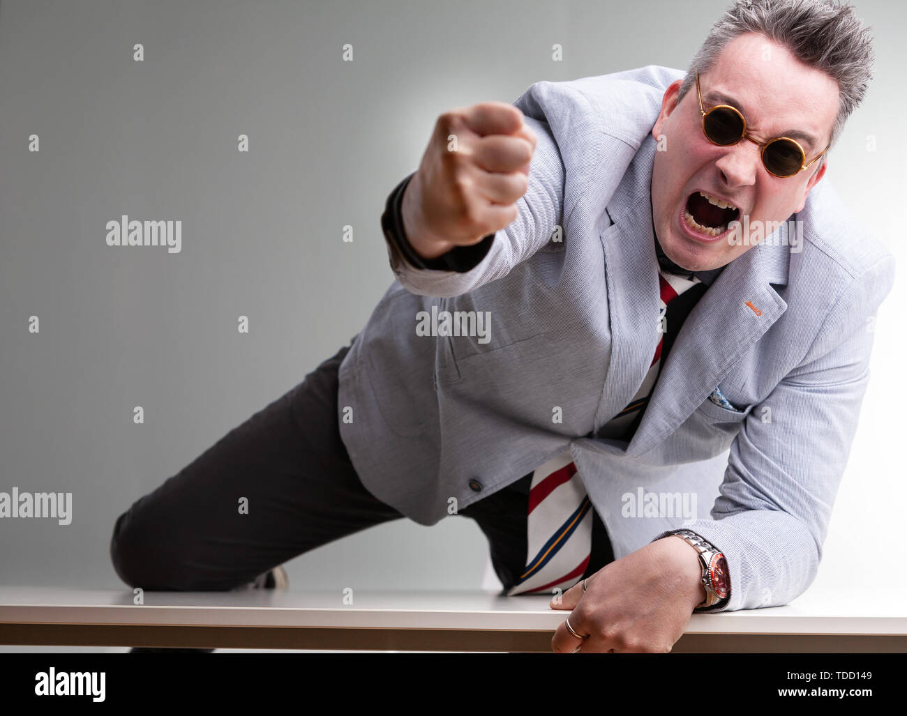 Furious belligerent man punching towards the camera leaning across the ...