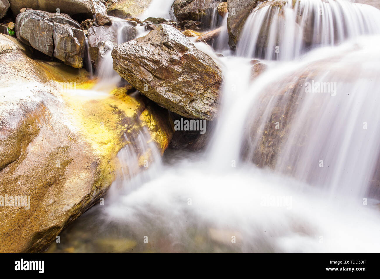 A clear stream flows over the rocks in the Tomur Peak Nature Reserve in ...