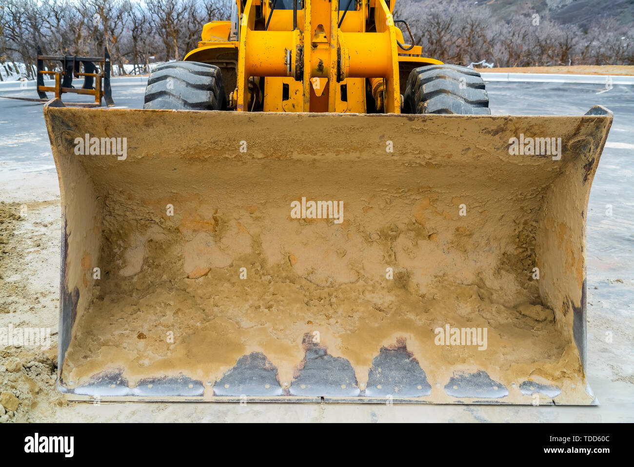 Dirty bucket of a bright yellow loader with huge black wheels. Snowy ...