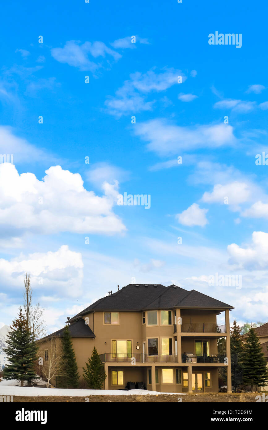 Three storey home with porch and balcony against blue sky with bright ...