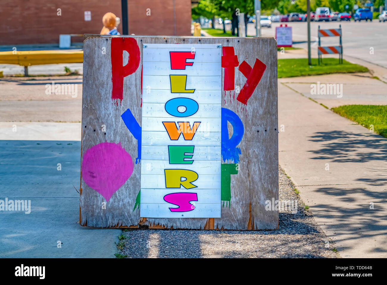 Flowers sign with a colorful font attached to a weathered wooden board ...