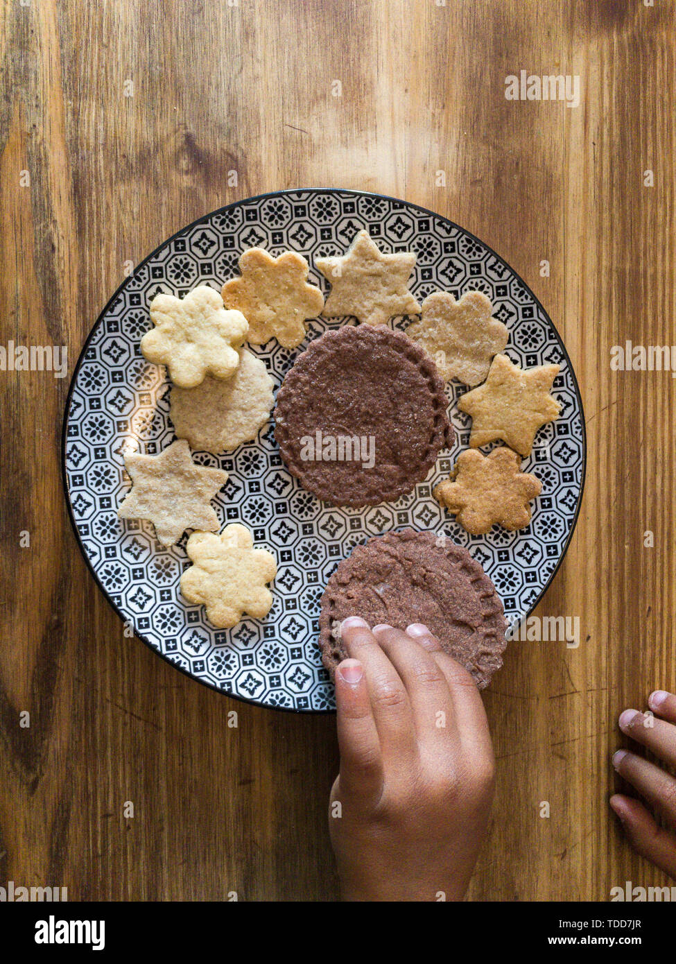 Kid's hand grabbing a cookie on a plate Stock Photo - Alamy