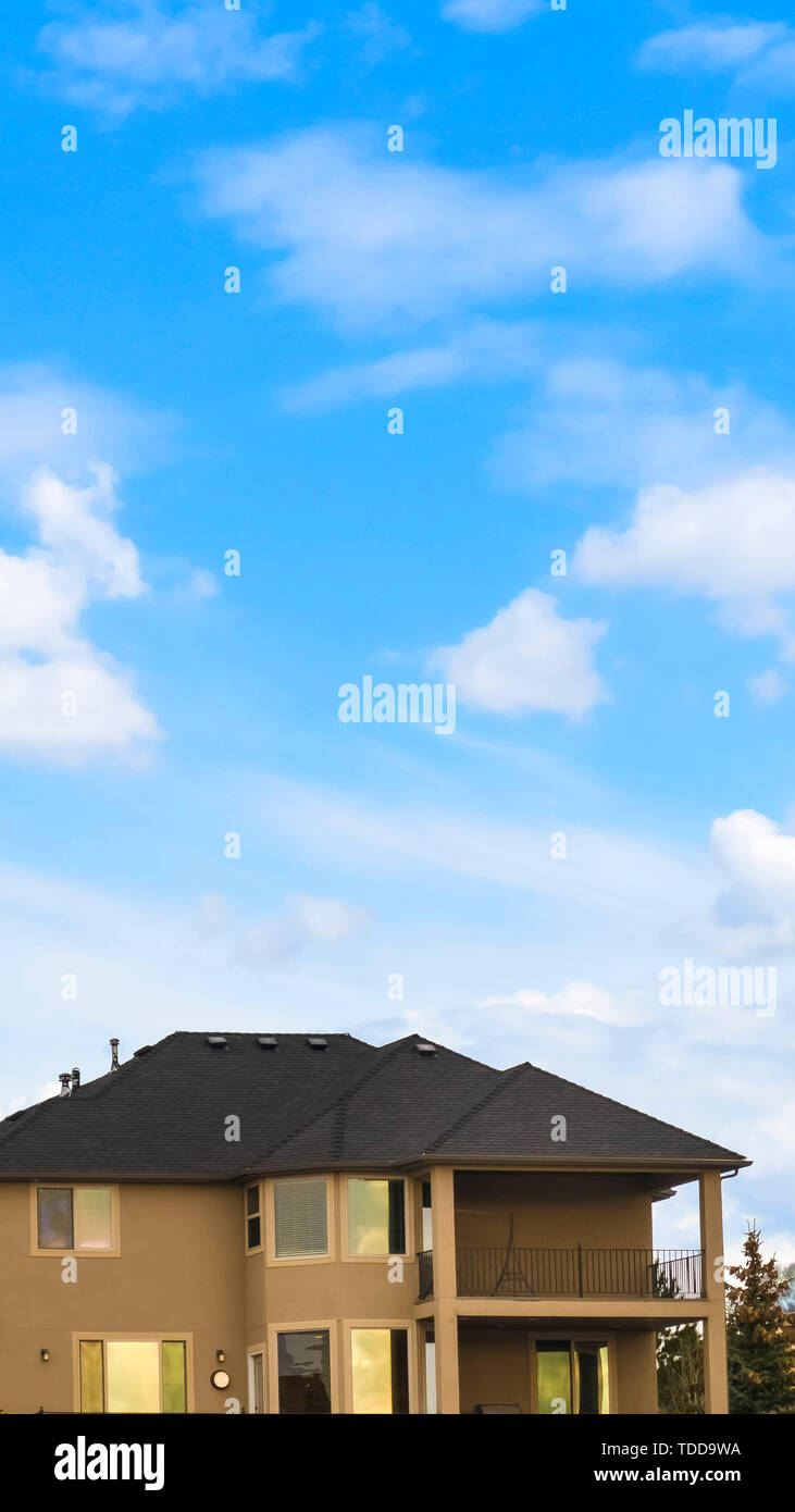 Vertical Three storey home with porch and balcony against blue sky with ...