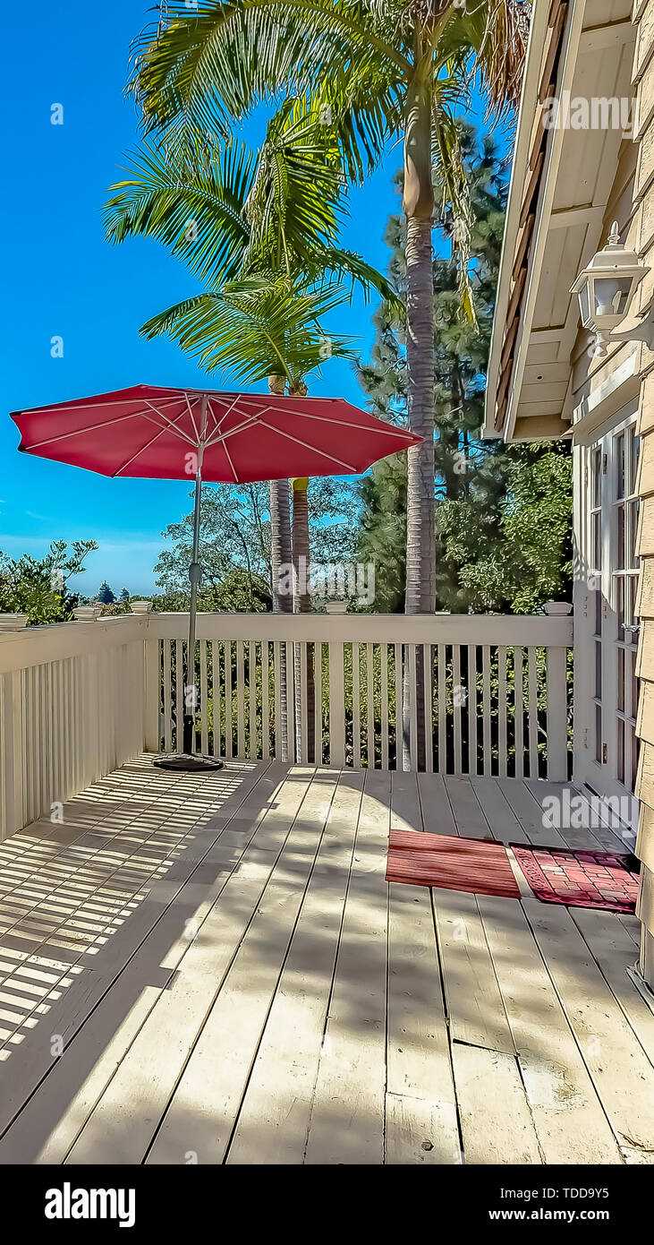 Vertical frame Balcony overlooking houses and trees against bright blue ...