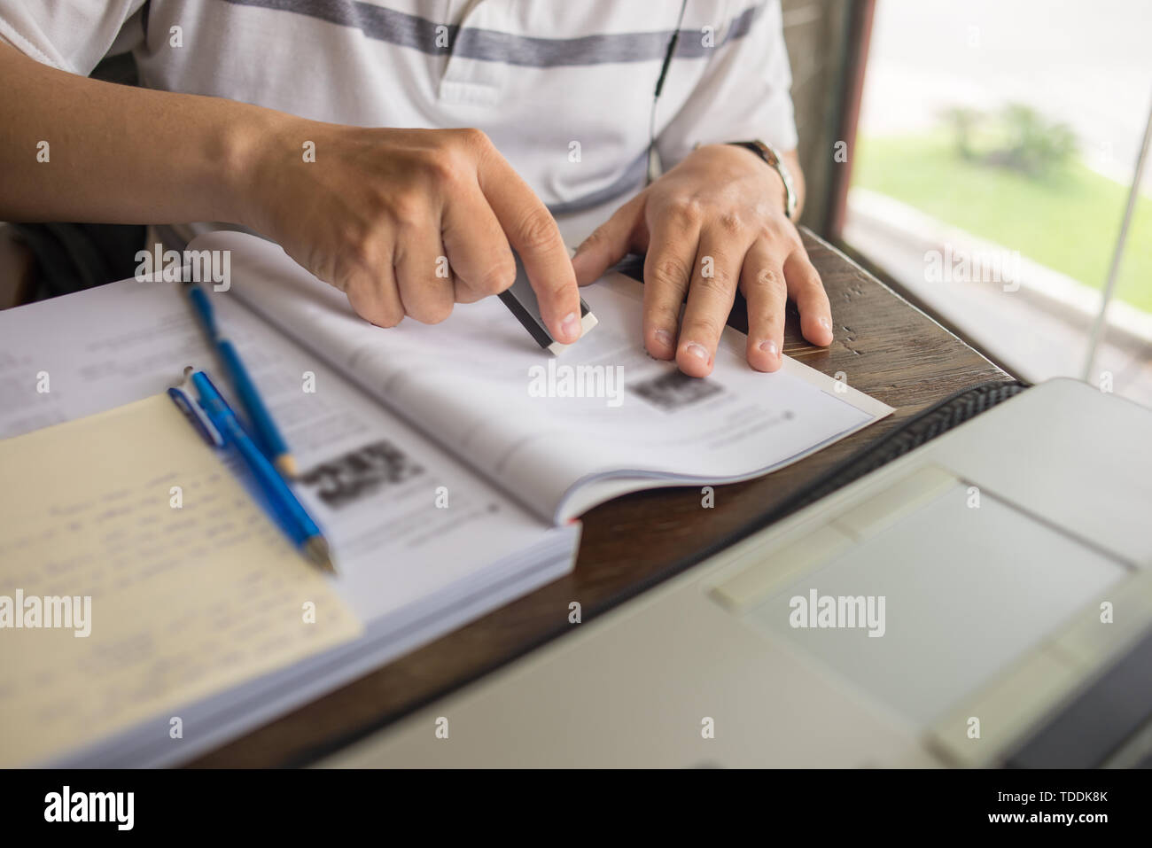 Closeup of student hand using eraser on workbook while studying Stock ...