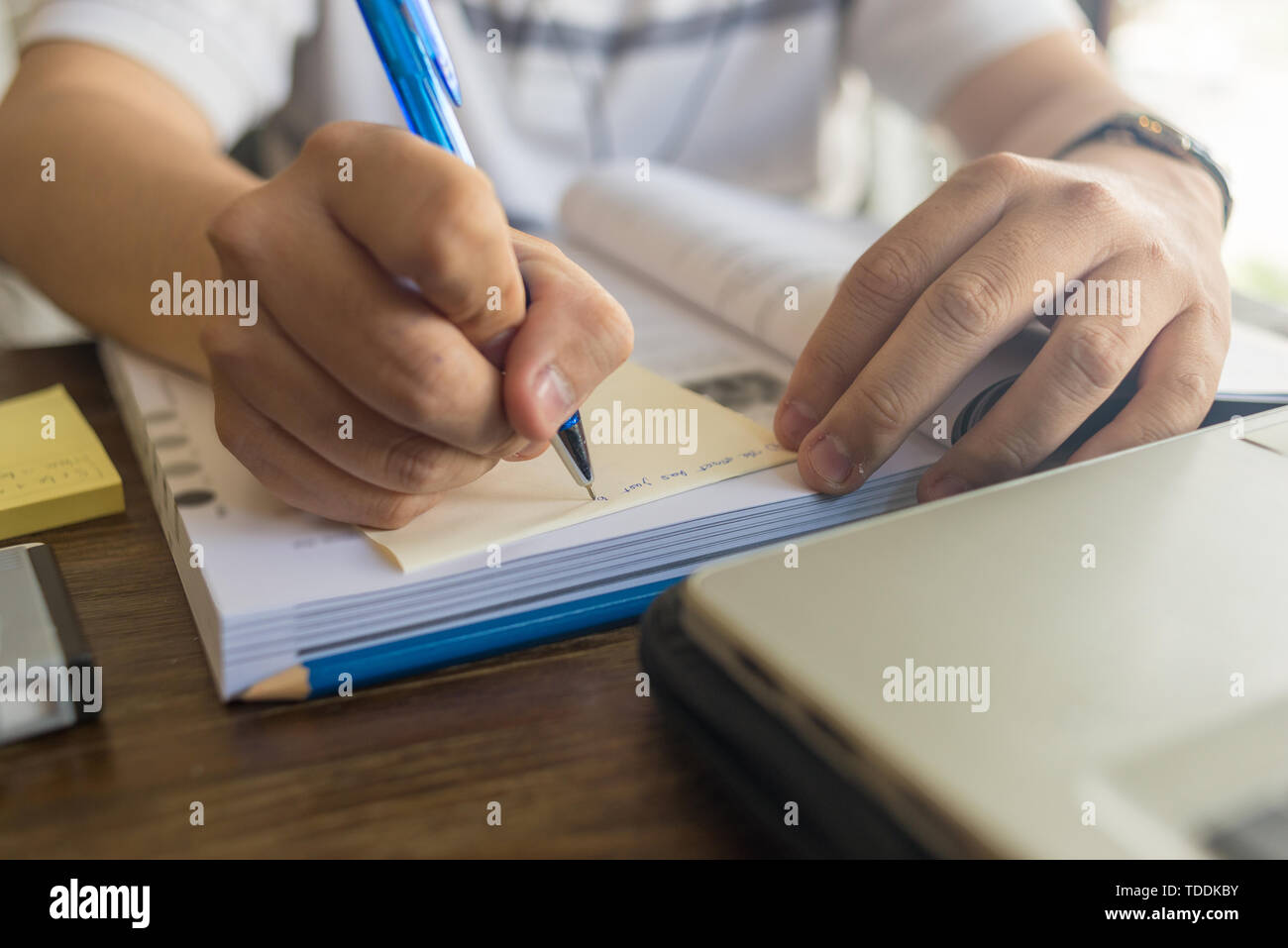 Closeup of human hand holding pen writing sticky note Stock Photo - Alamy