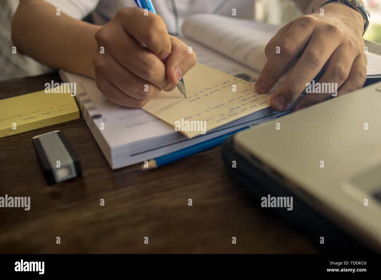 Close up of student hand writing sticky note while studying Stock Photo ...