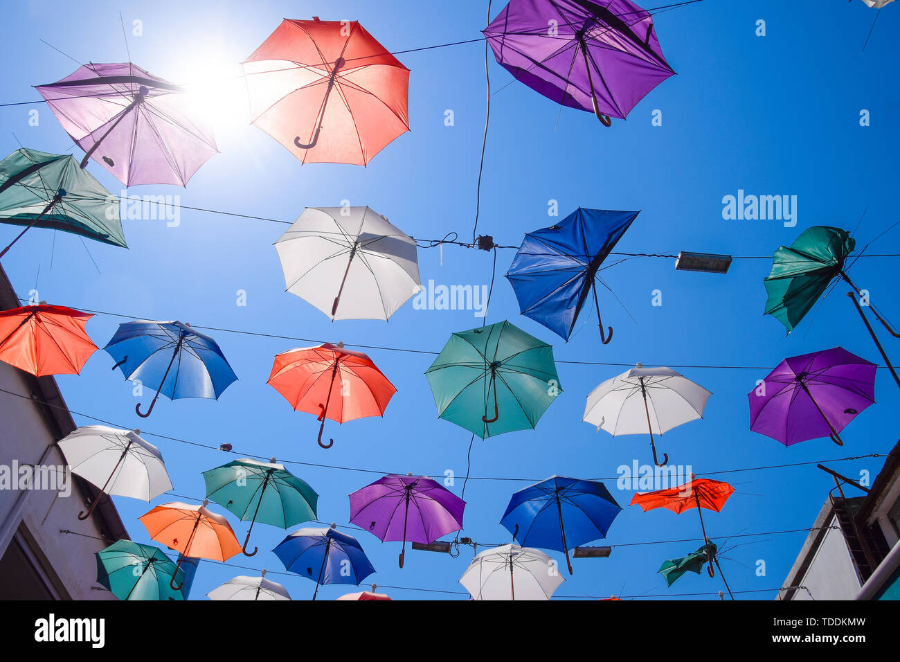 hanging umbrellas against the blue sky, walk through the streets of ...