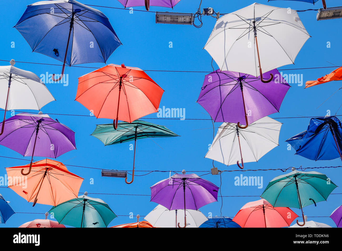 hanging umbrellas against the blue sky, walk through the streets of ...