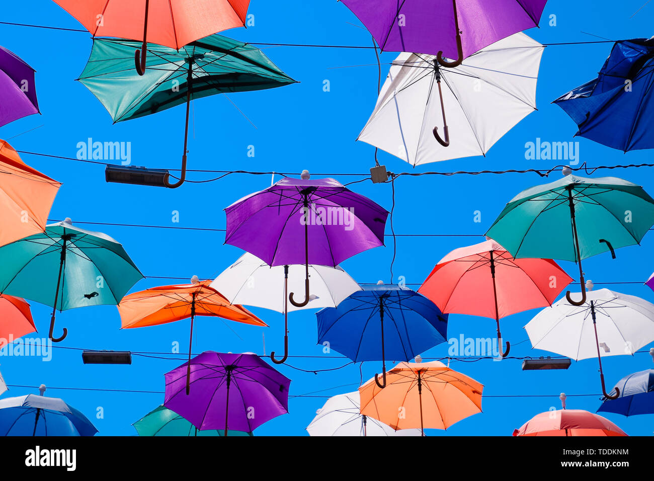 hanging umbrellas against the blue sky, walk through the streets of ...