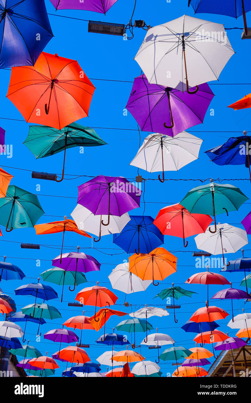 hanging umbrellas against the blue sky, walk through the streets of ...