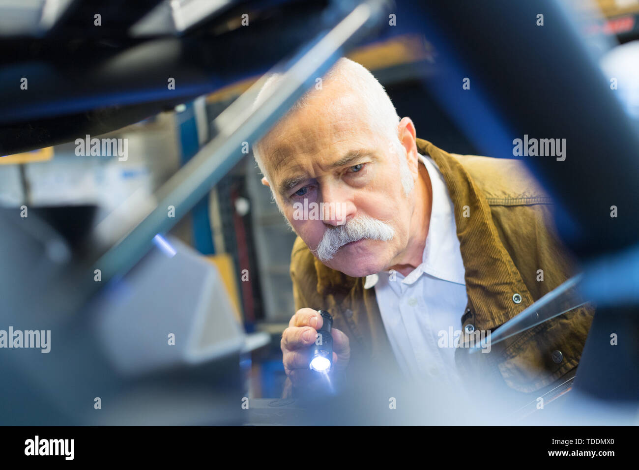 mechanic using torch to inspect vehicle Stock Photo - Alamy