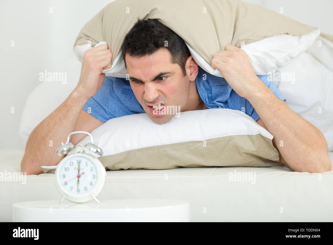 man shouting angrily at alarm clock which has awoken him Stock Photo ...