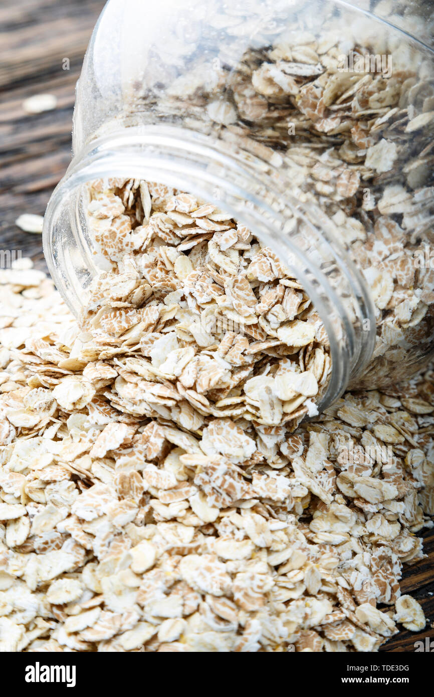 Oat flakes spilling out of glass jar on wooden background, concept for ...