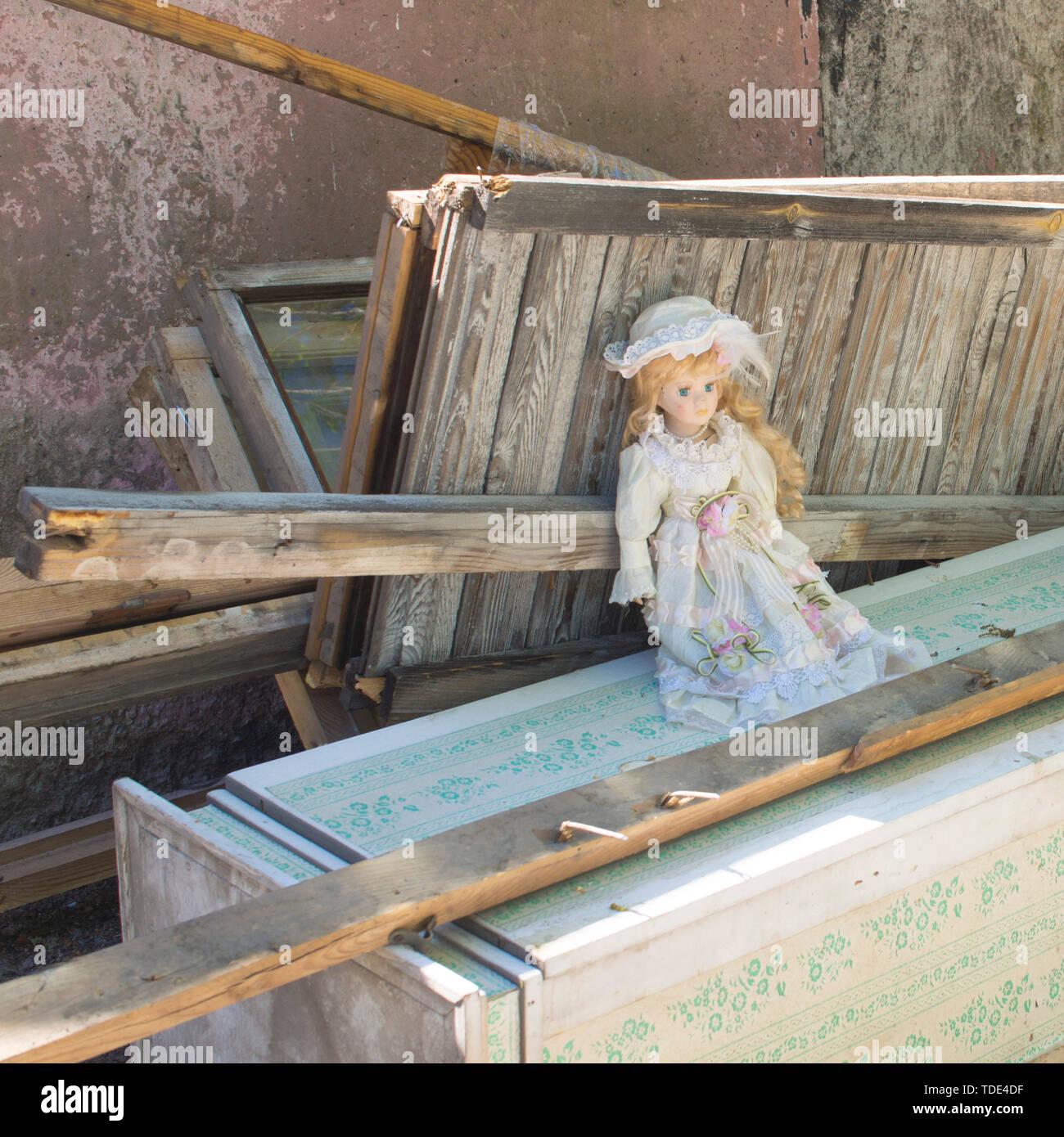 a pretty broken vintage doll in a beautiful dress sits in the trash in ...