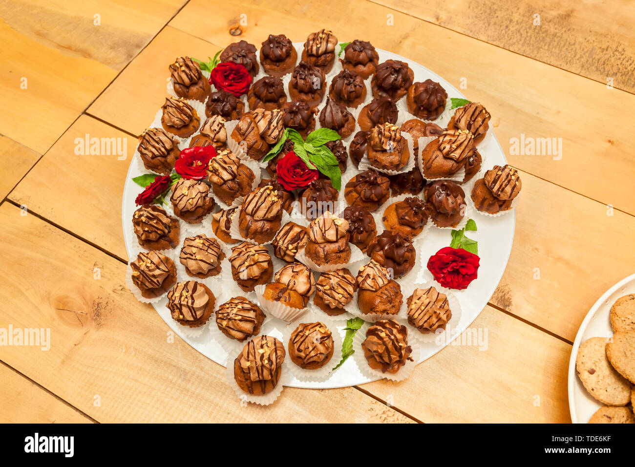 Small assorted cakes lined up decorated on dessert buffet with red rose ...