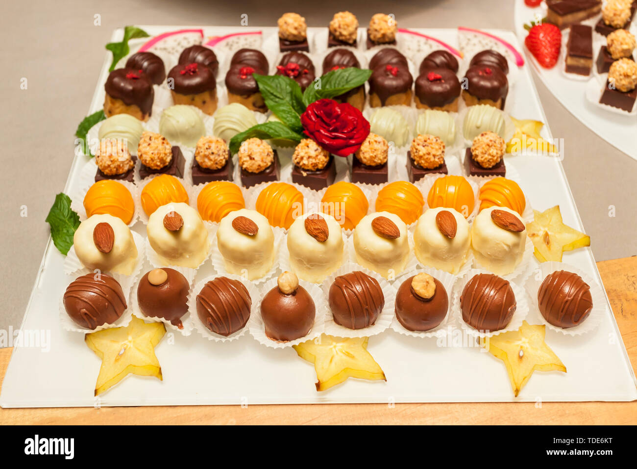 Small assorted cakes lined up decorated on dessert buffet with red rose ...