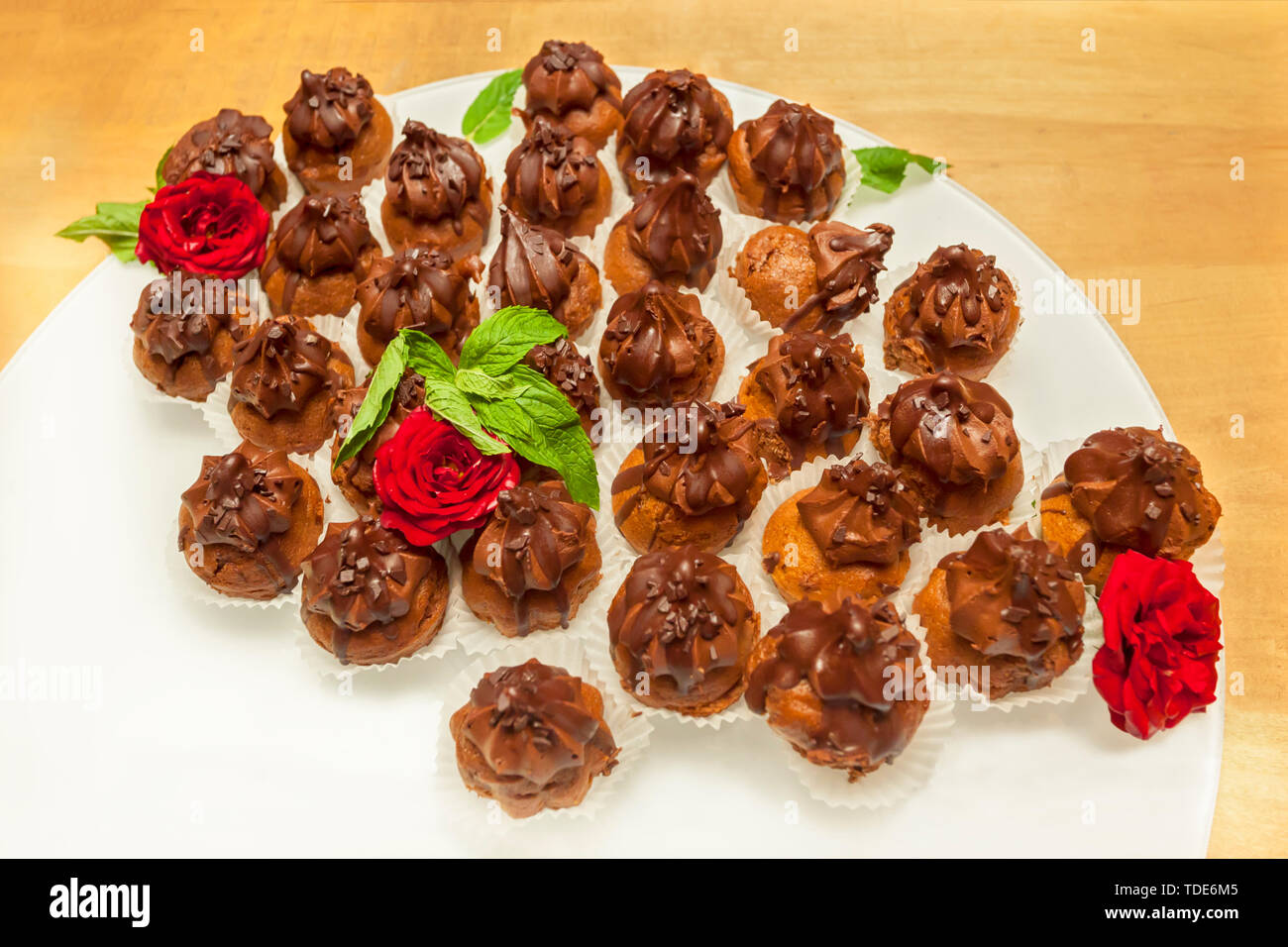 Small assorted cakes lined up decorated on dessert buffet with red rose ...