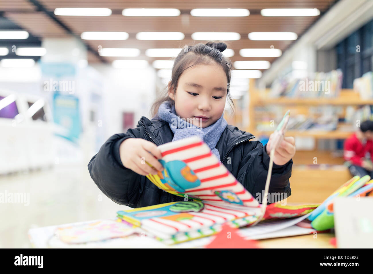 Little Asian girl reading in the library Stock Photo - Alamy