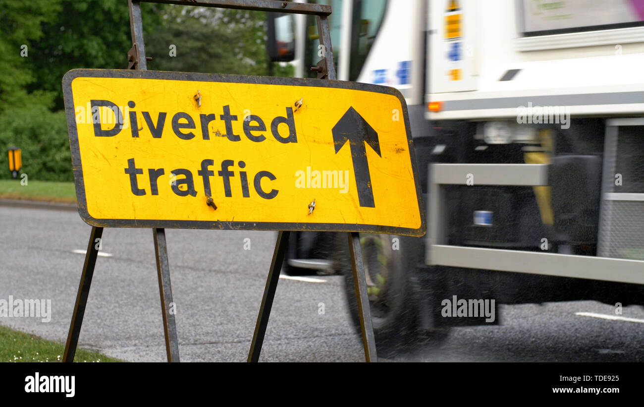 Diverted traffic sign with cars and trucks passing on background on ...