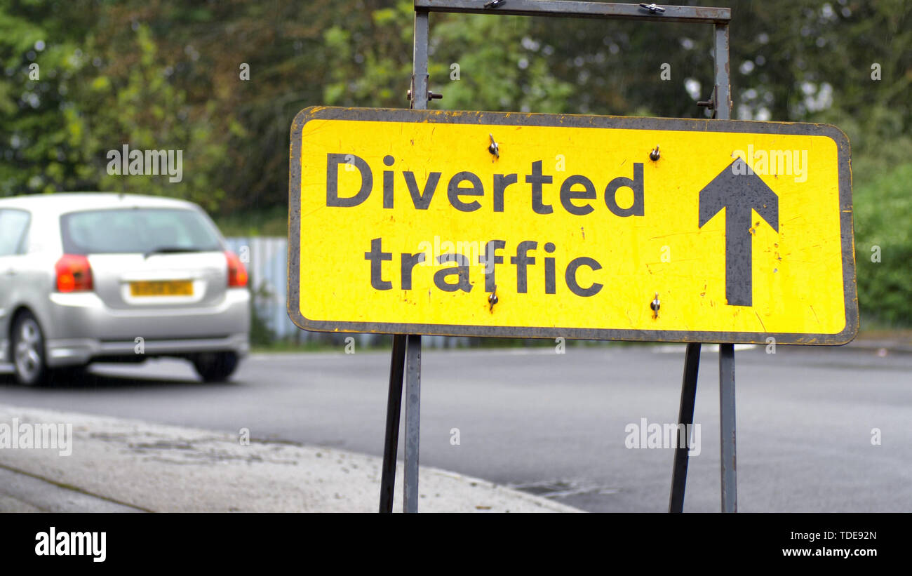 Diverted traffic sign with cars and trucks passing on background on ...