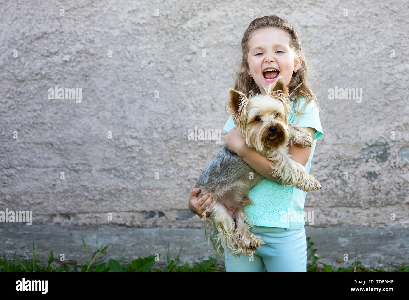 cute girl in a blue t-shirt with dimples on her cheeks holding a dog ...