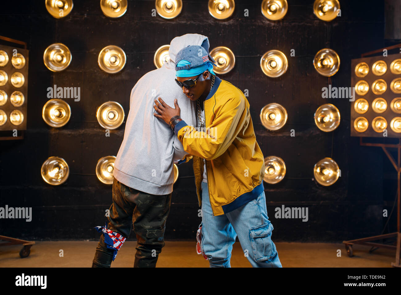 Two black rappers in caps hugging on stage Stock Photo - Alamy
