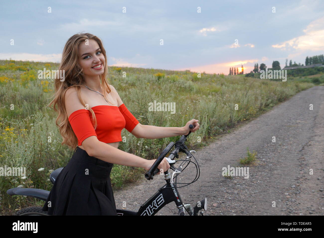 Beautiful girl riding bike at fields at sunset Stock Photo - Alamy