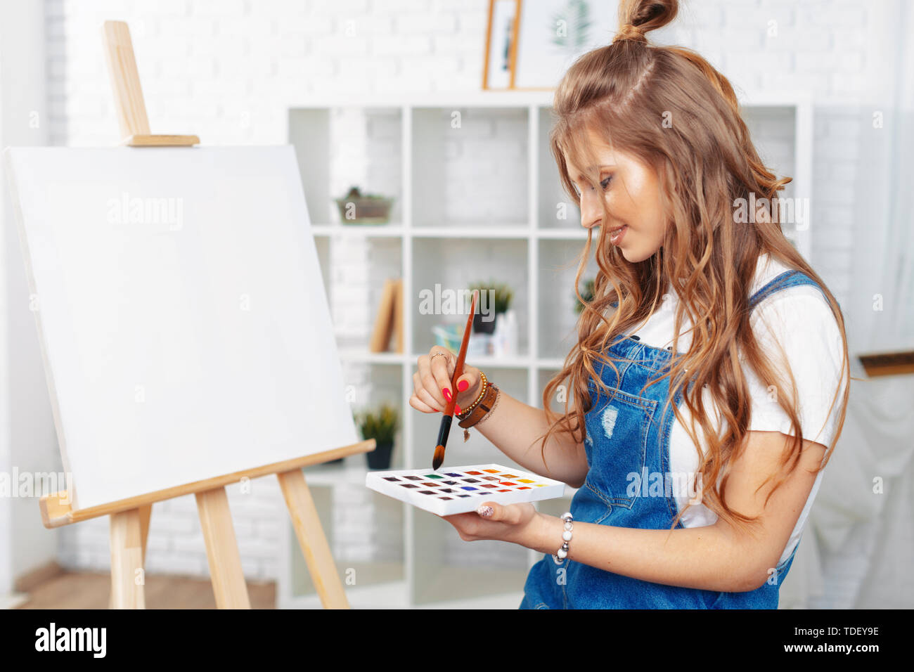 Pretty talented female painter painting on easel Stock Photo - Alamy