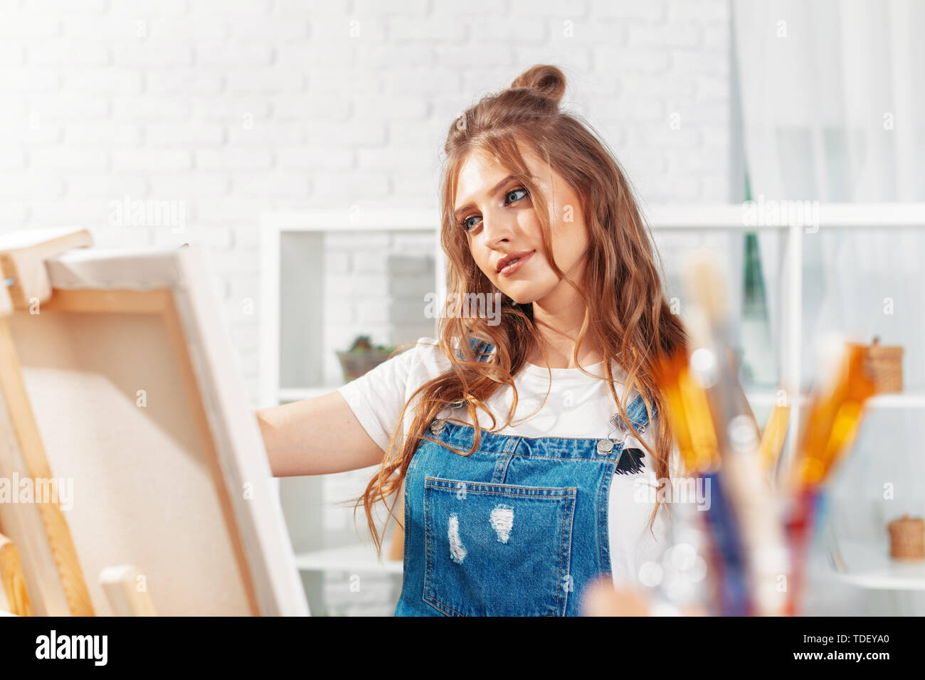 Pretty talented female painter painting on easel Stock Photo - Alamy