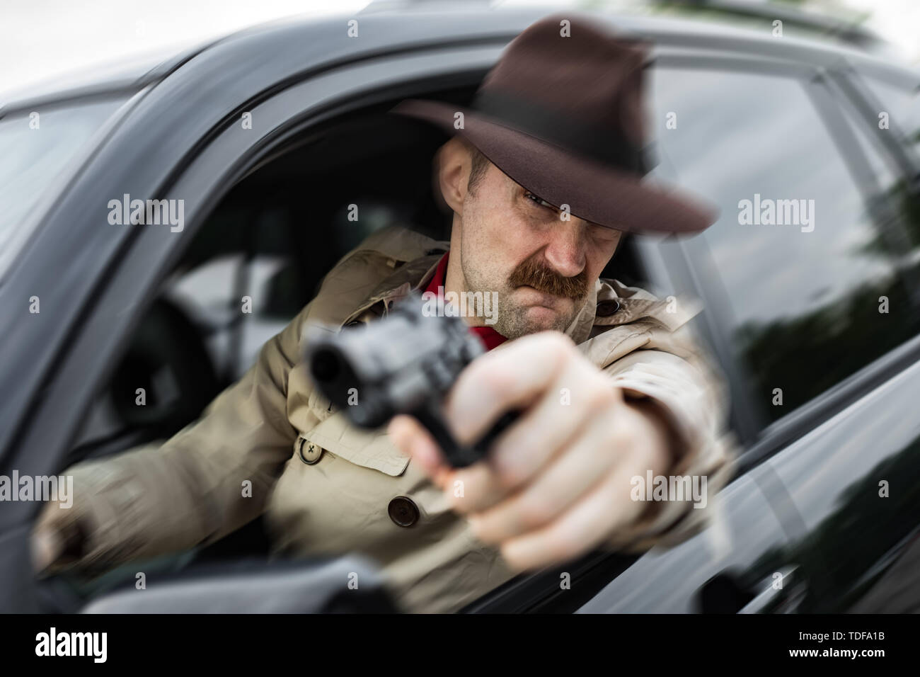 Detective chasing a criminal by car and shooting o him with his gun ...
