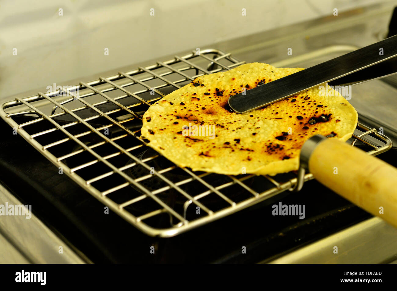 Papad an Indian snack being roasted on a gas stove Stock Photo - Alamy