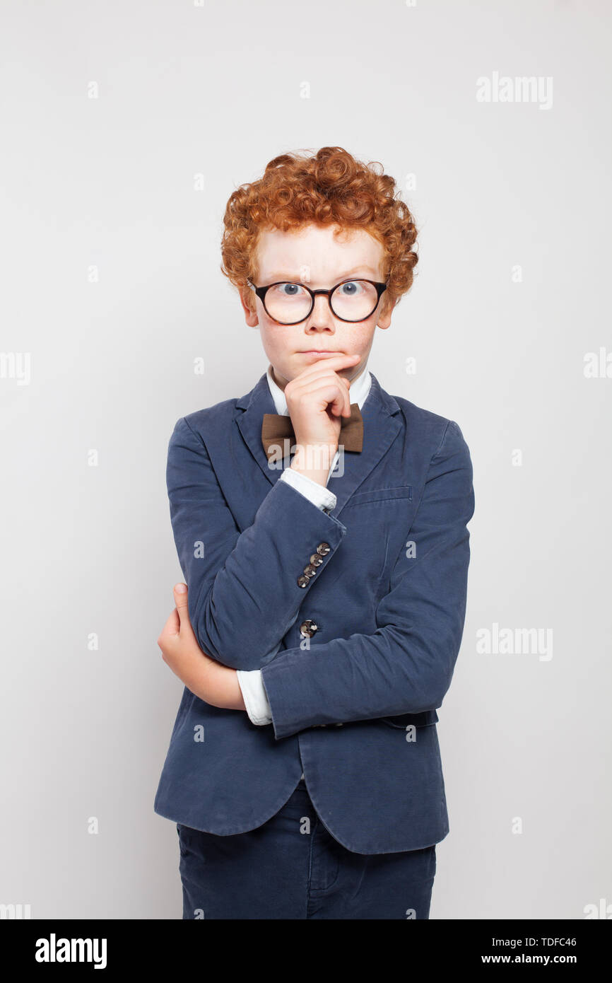 Thinking child boy with ginger hair wearing glasses and suit on white ...