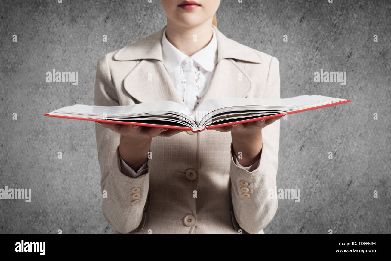 Business woman holding open book on background of grey wall. Business ...