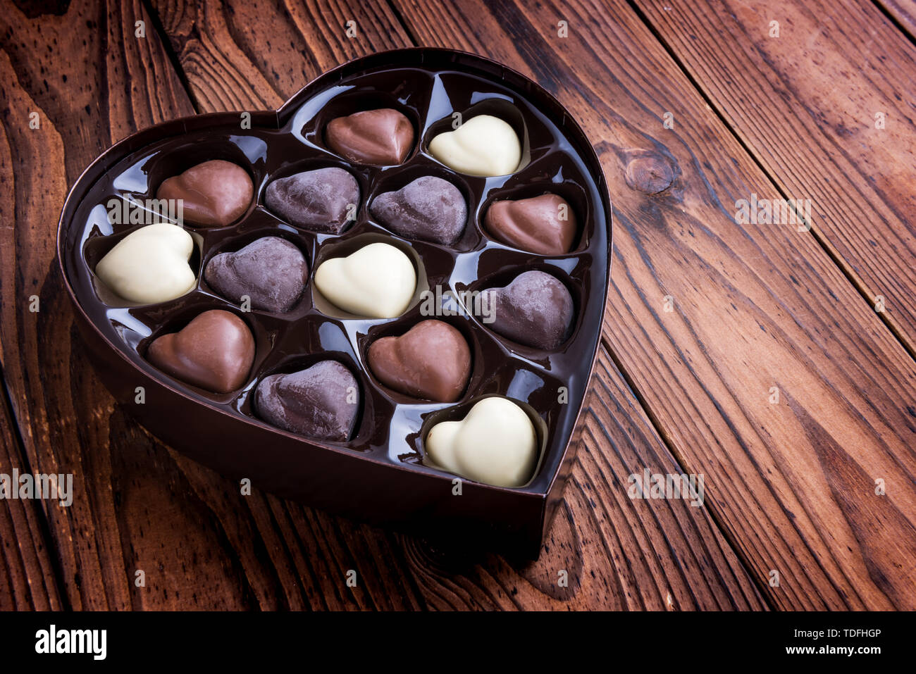 Open heart-shaped box of chocolates, heart-shaped chocolates on wooden ...